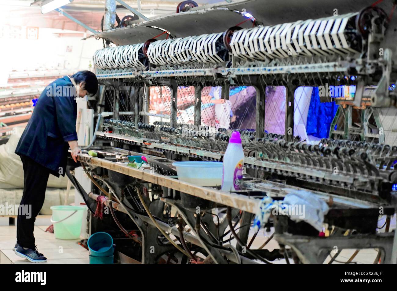 Silk factory Shanghai, A worker cleans and maintains a machine in a ...