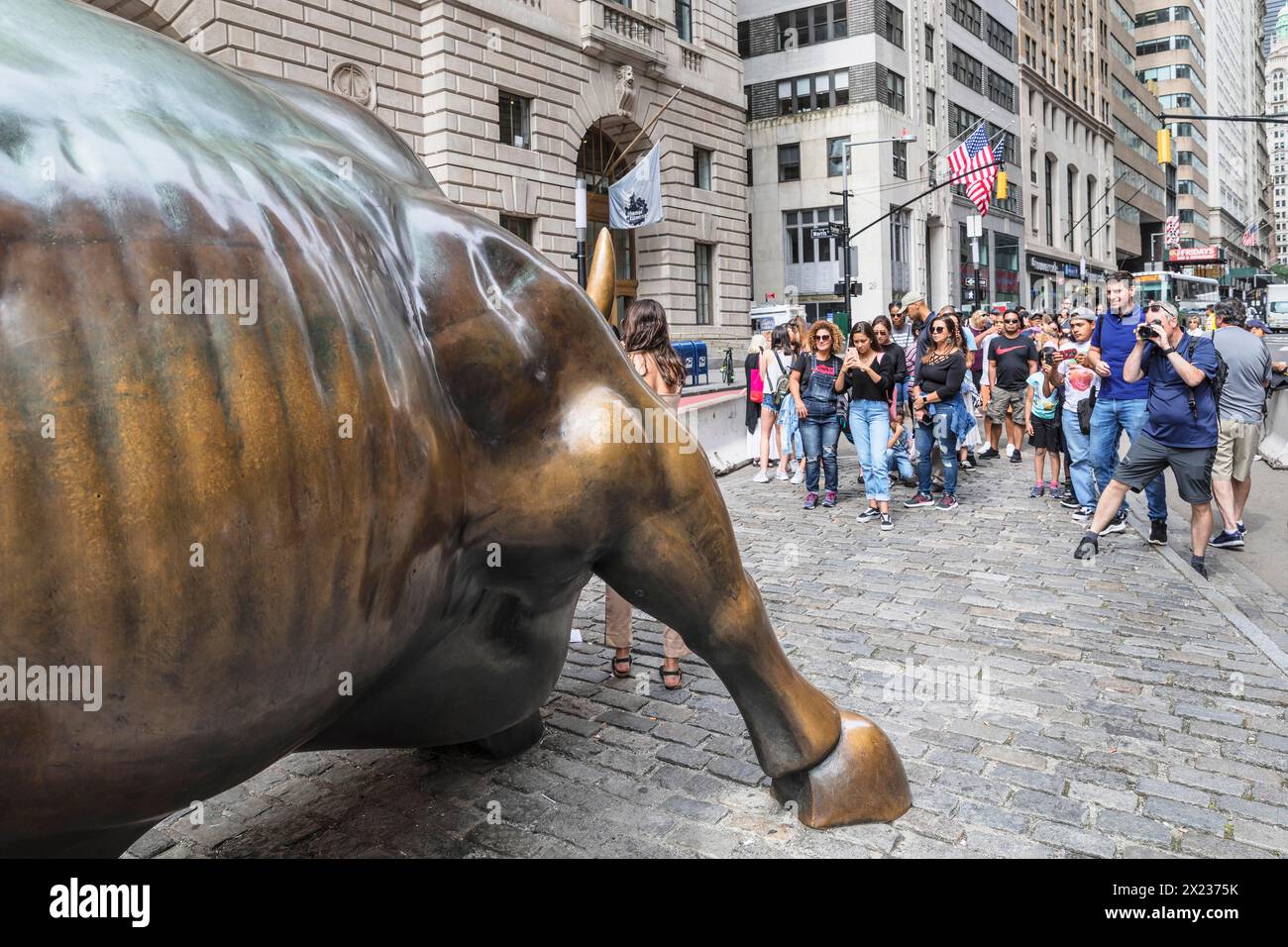 Tourists taking pictures in front of the bronze statue of the Charging Bull, Wall Street ...