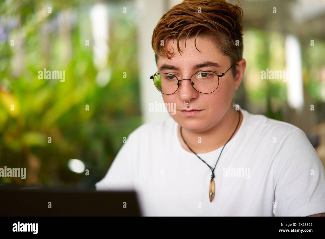 Transgender pro focuses laptop work in office. Inclusive environment ...