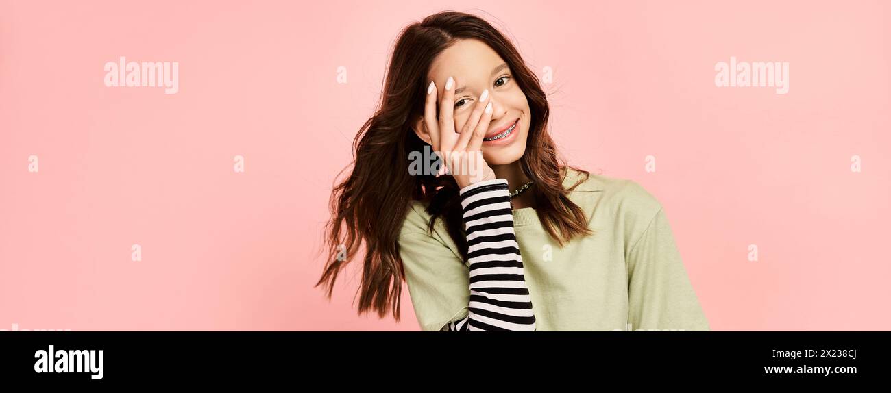 A stylish young woman in vibrant attire gracefully holds her hand up to ...