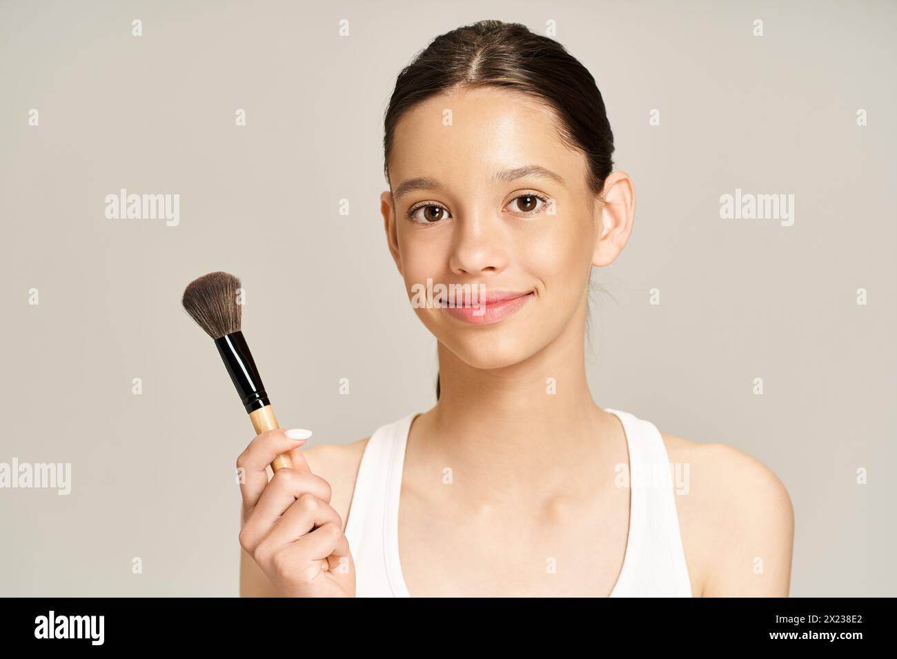 A stylish teenage girl holds a makeup brush in her hand, getting ready ...