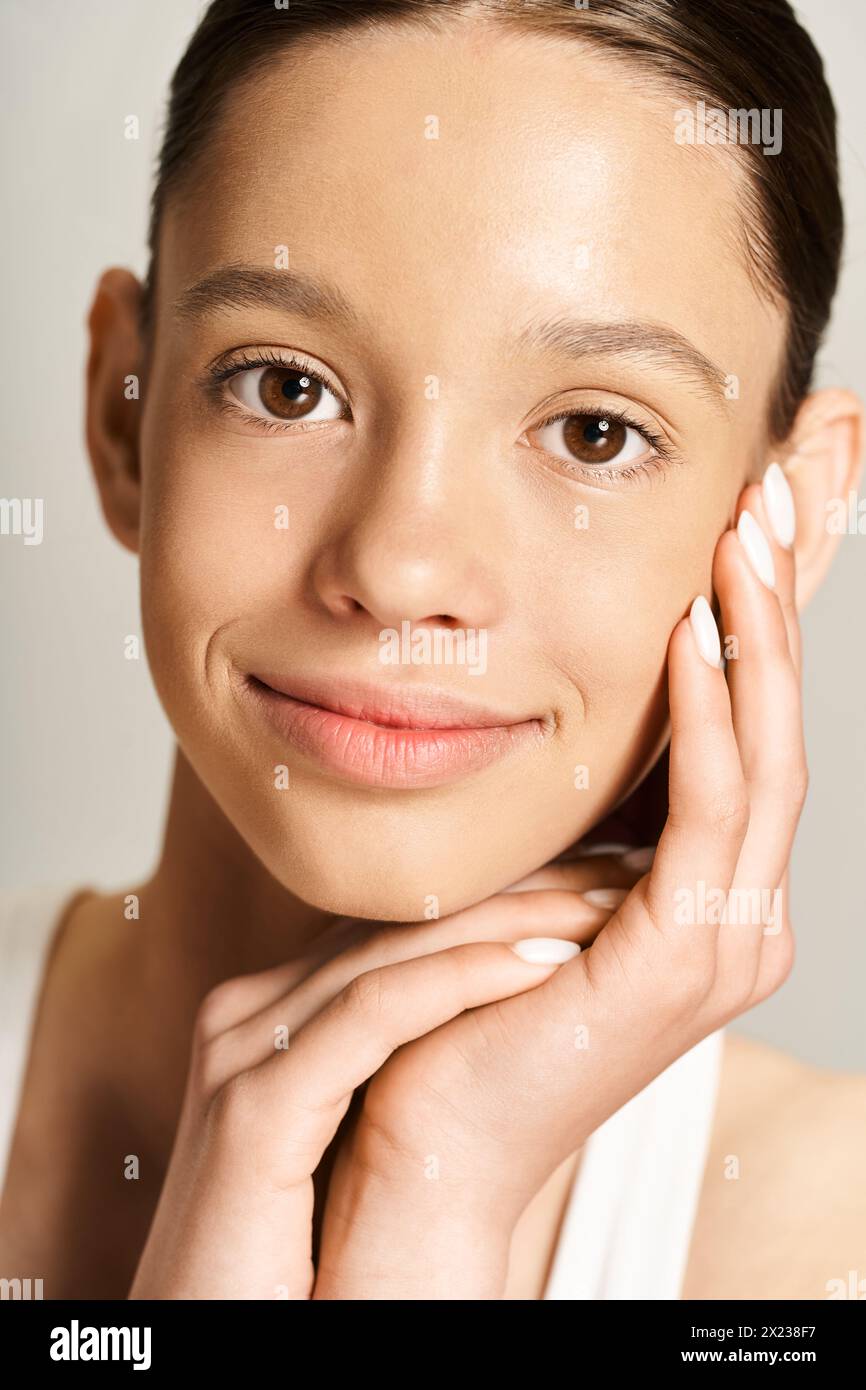 A stylish teenage girl striking a pose with hands on her face ...
