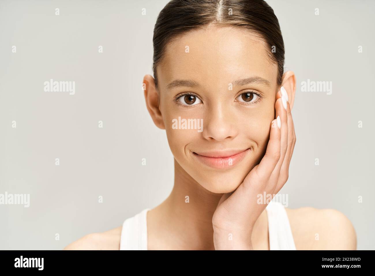 A stylish teenage girl joyfully smiles, hands on face, exuding positive ...
