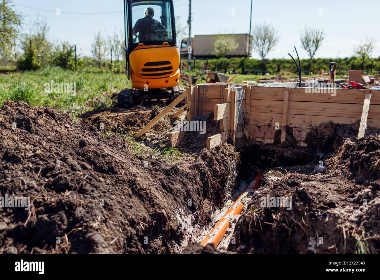 Excavator digging trench in soil for sewage pipeline during building ...