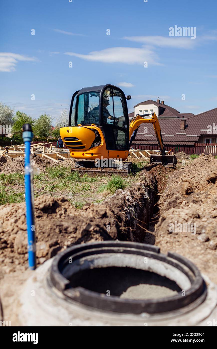 Excavator digging trench in soil for pipeline during building house ...