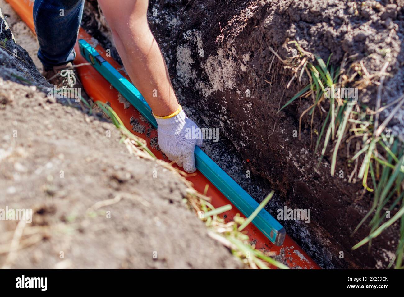 Plumber measuring slope of assembled sewage pipes using spirit level in ...