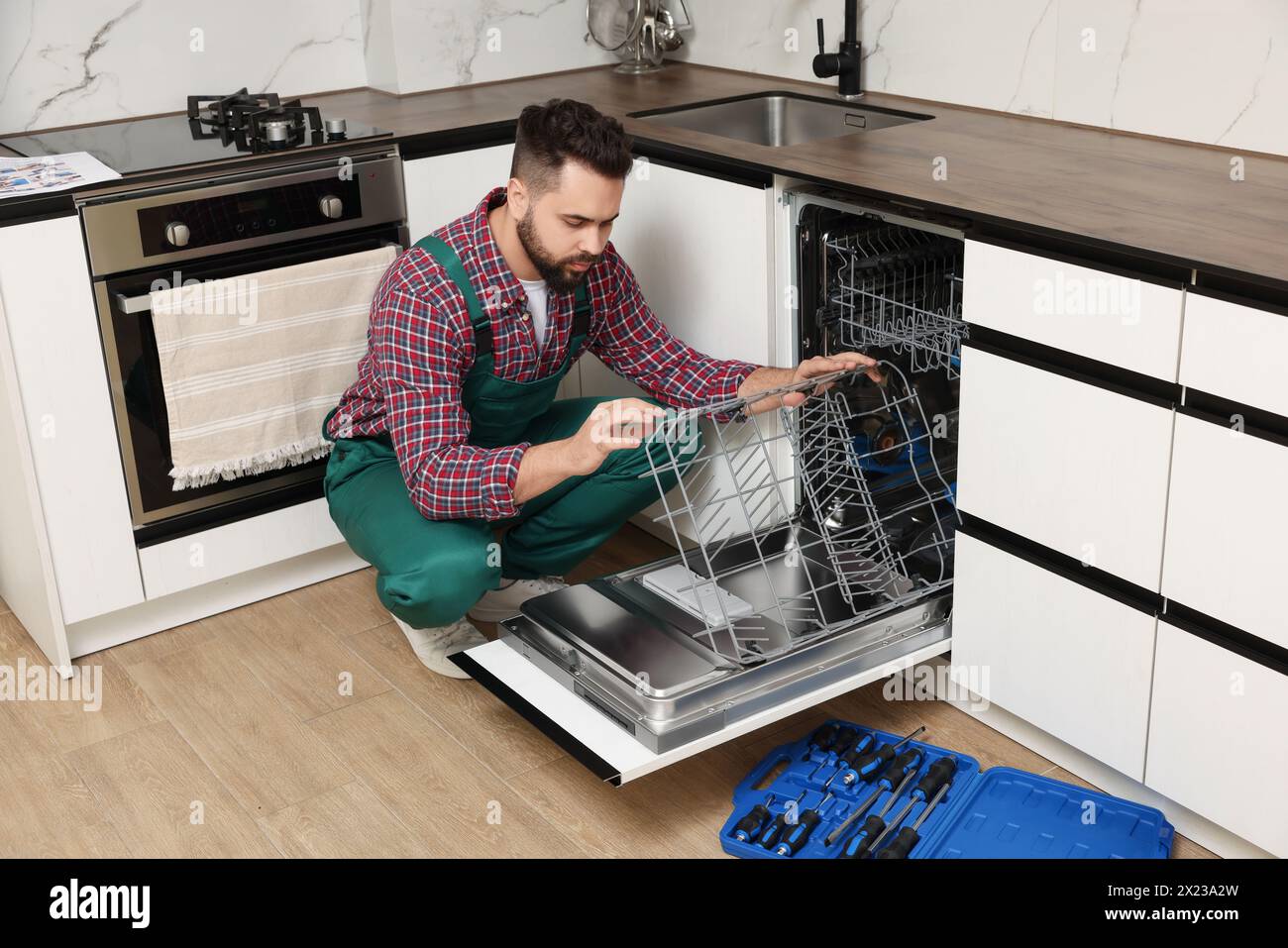 Serviceman examining dishwasher lower rack in kitchen Stock Photo - Alamy