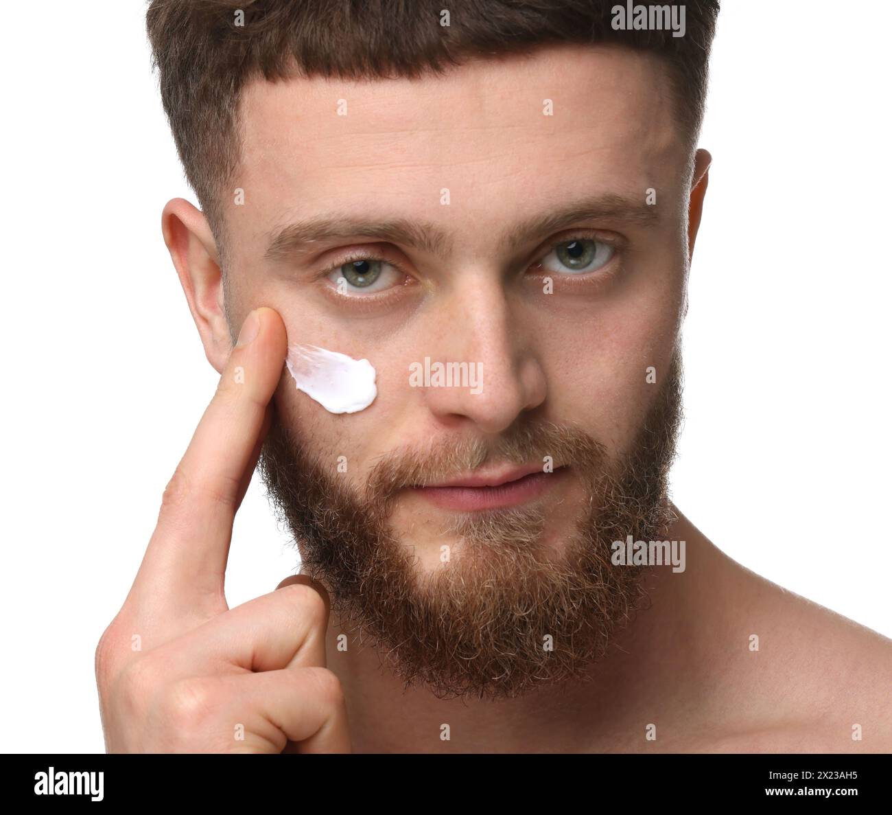 Handsome man applying moisturizing cream onto his face on white ...