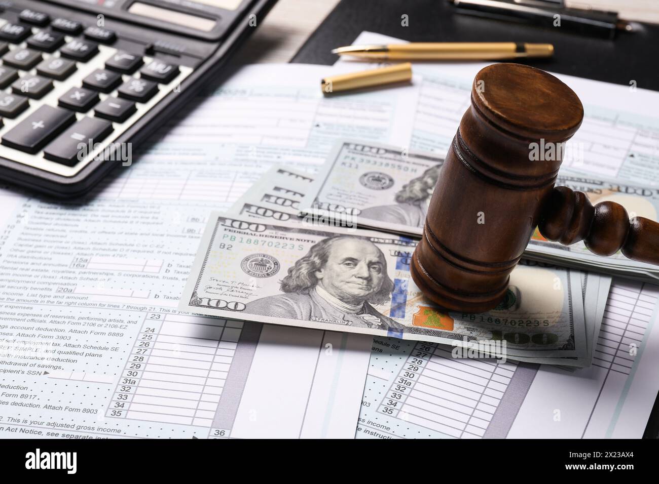Tax return forms, dollar banknotes, gavel and calculator on table ...
