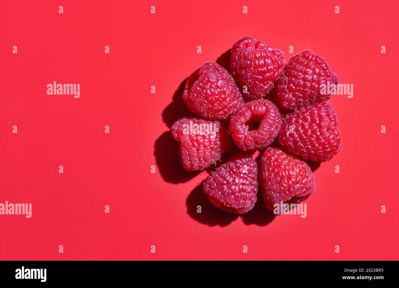 Raspberries on a red background in a flower design Stock Photo - Alamy