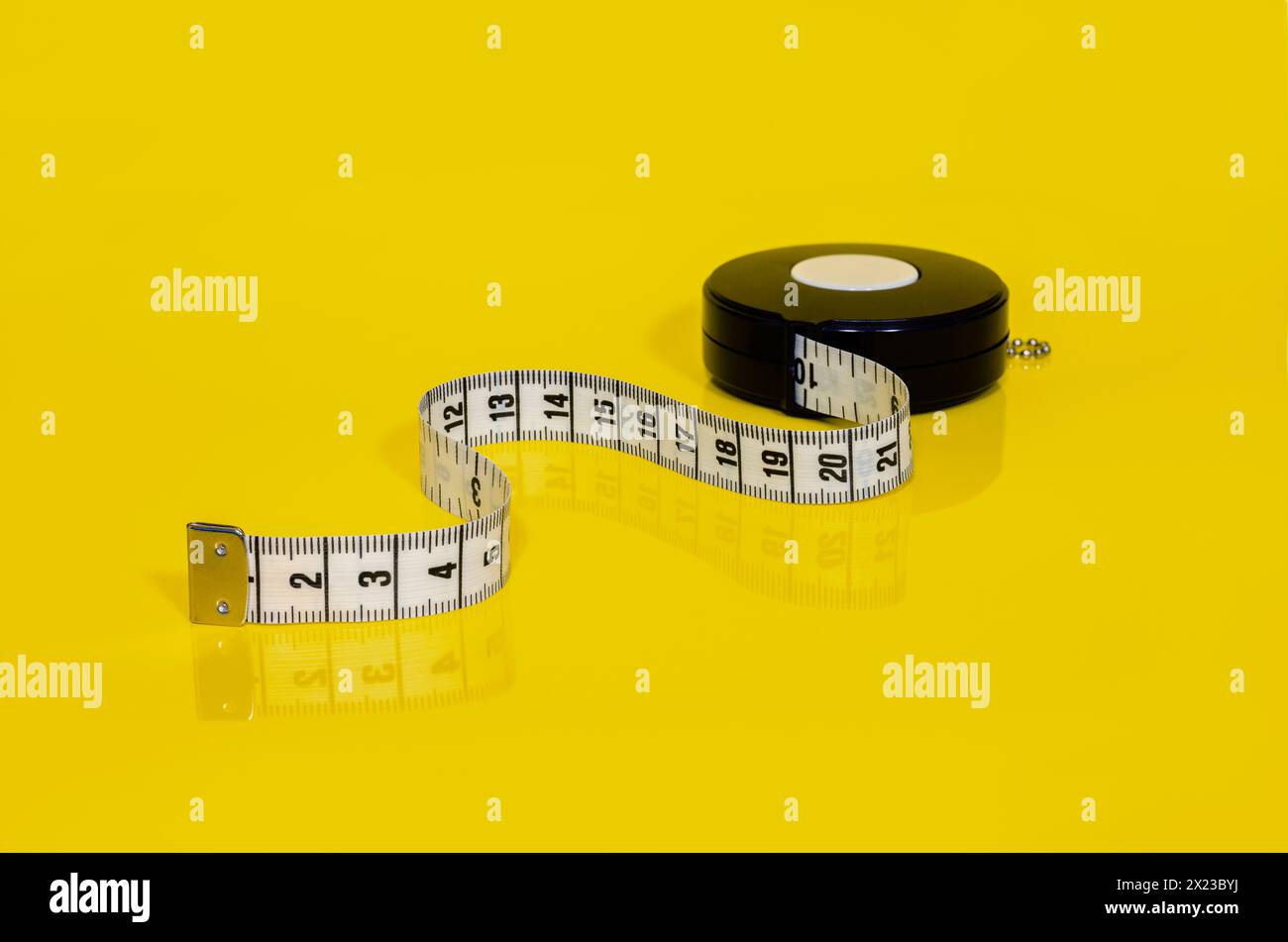 Retractable tape measure in centimetres on bright yellow background ...