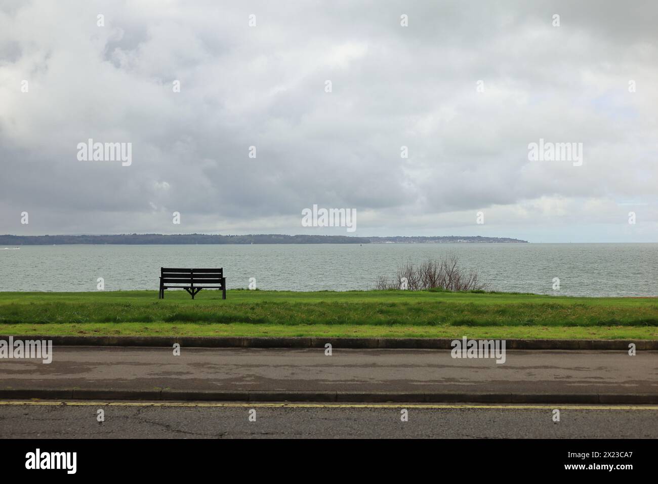 A solitary bench on green grass and overlooking a channel of water ...