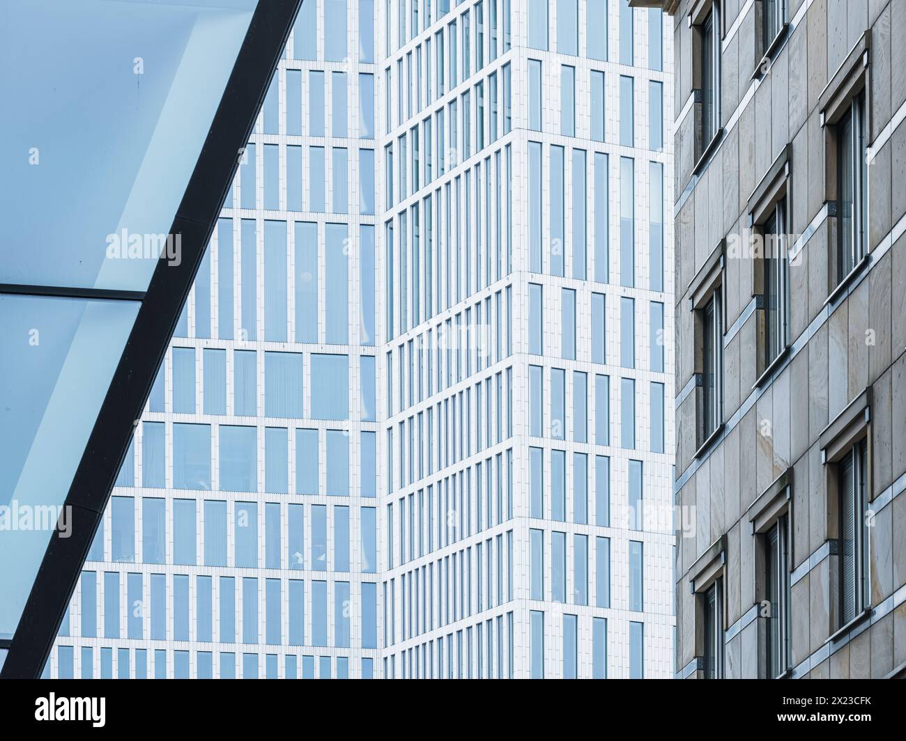 A tall building with numerous windows stands next to another building ...