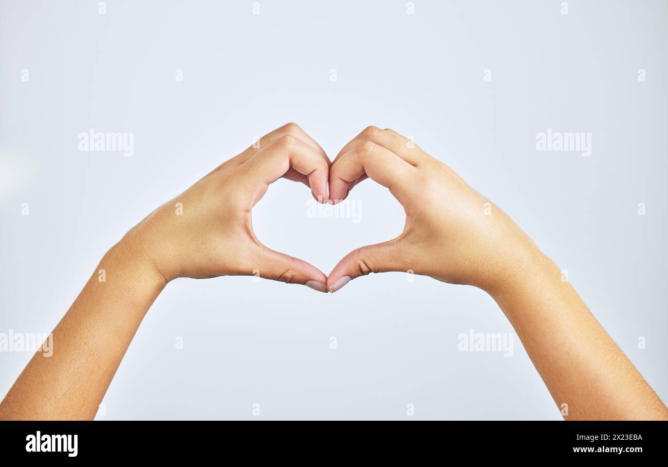 Hands, closeup and person in studio with heart sign, gesture or symbol ...
