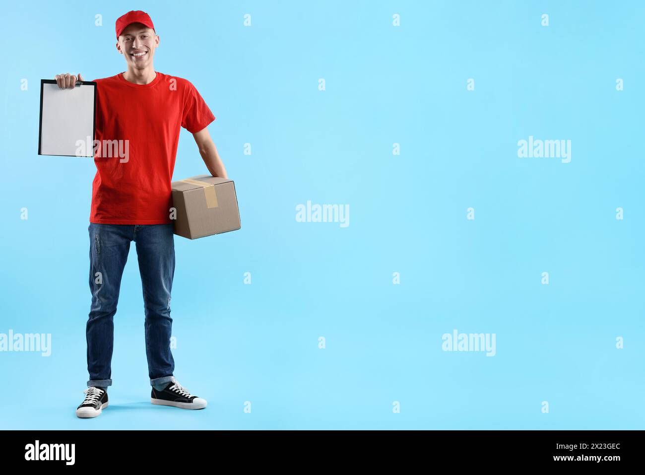 Happy courier with parcel and clipboard on light blue background. Space ...