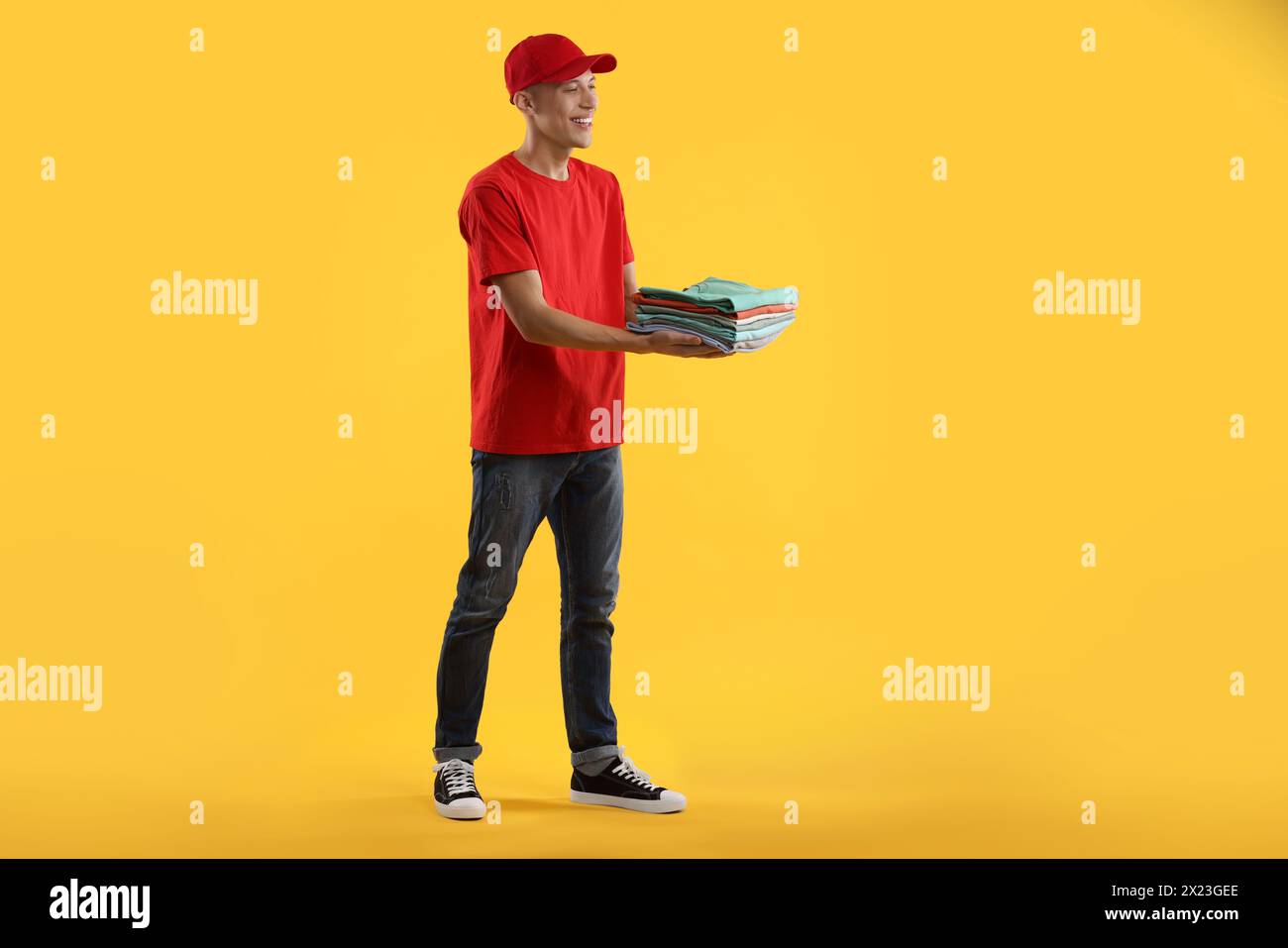 Dry-cleaning delivery. Happy courier holding folded clothes on orange ...