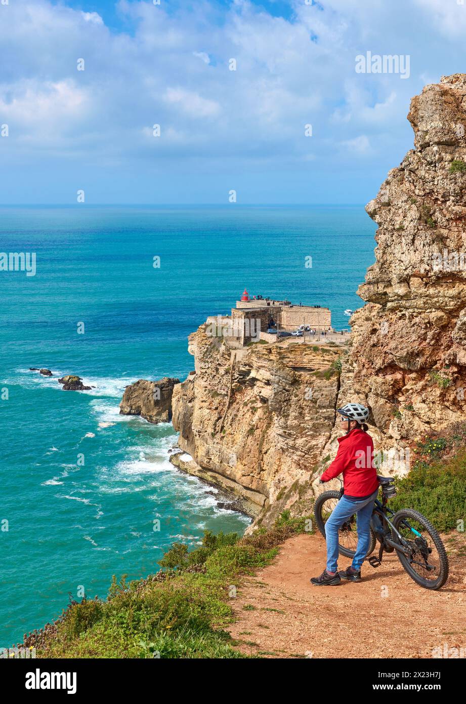nice senior woman riding her electric mountain bike on the rocky cliffs ...