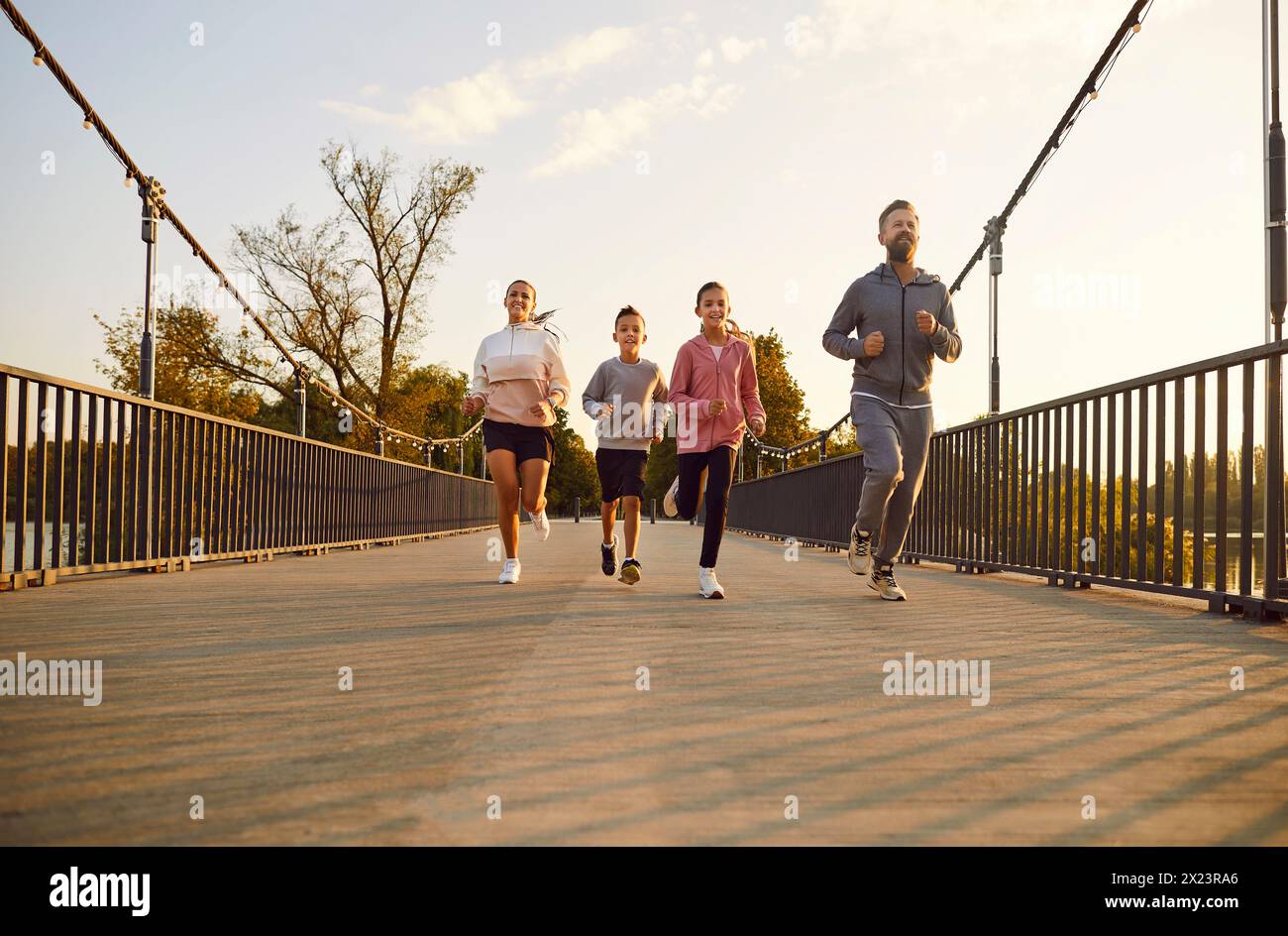 Happy Family With Two Children Jogging In The City Park At Sunset Stock ...