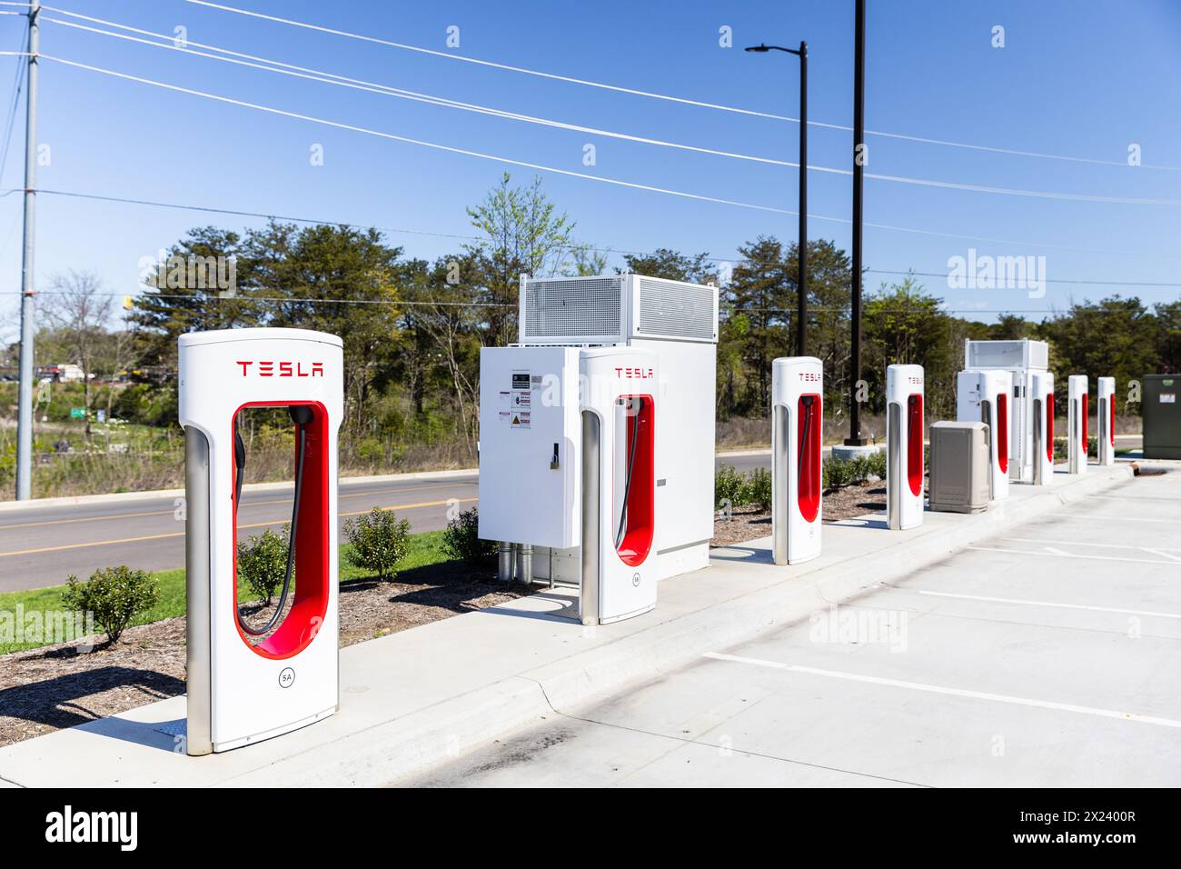 A row of white and red Tesla charging stations in a parking lot with no ...