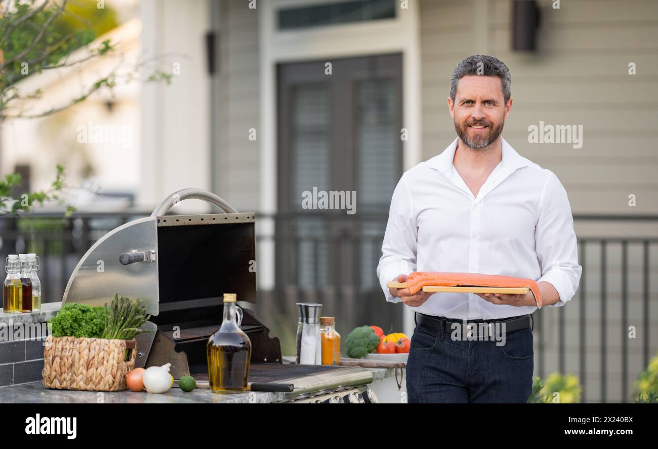 Male chef grilling and barbequing salmon fillet in garden. Barbecue ...