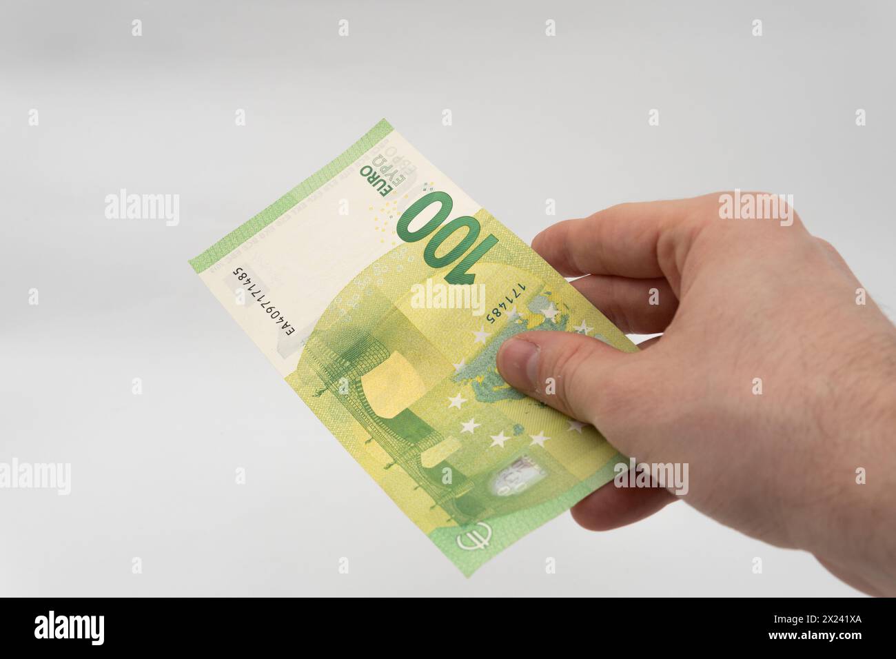 Man holding 100 EUR banknote paper currency Euro isolated on white ...