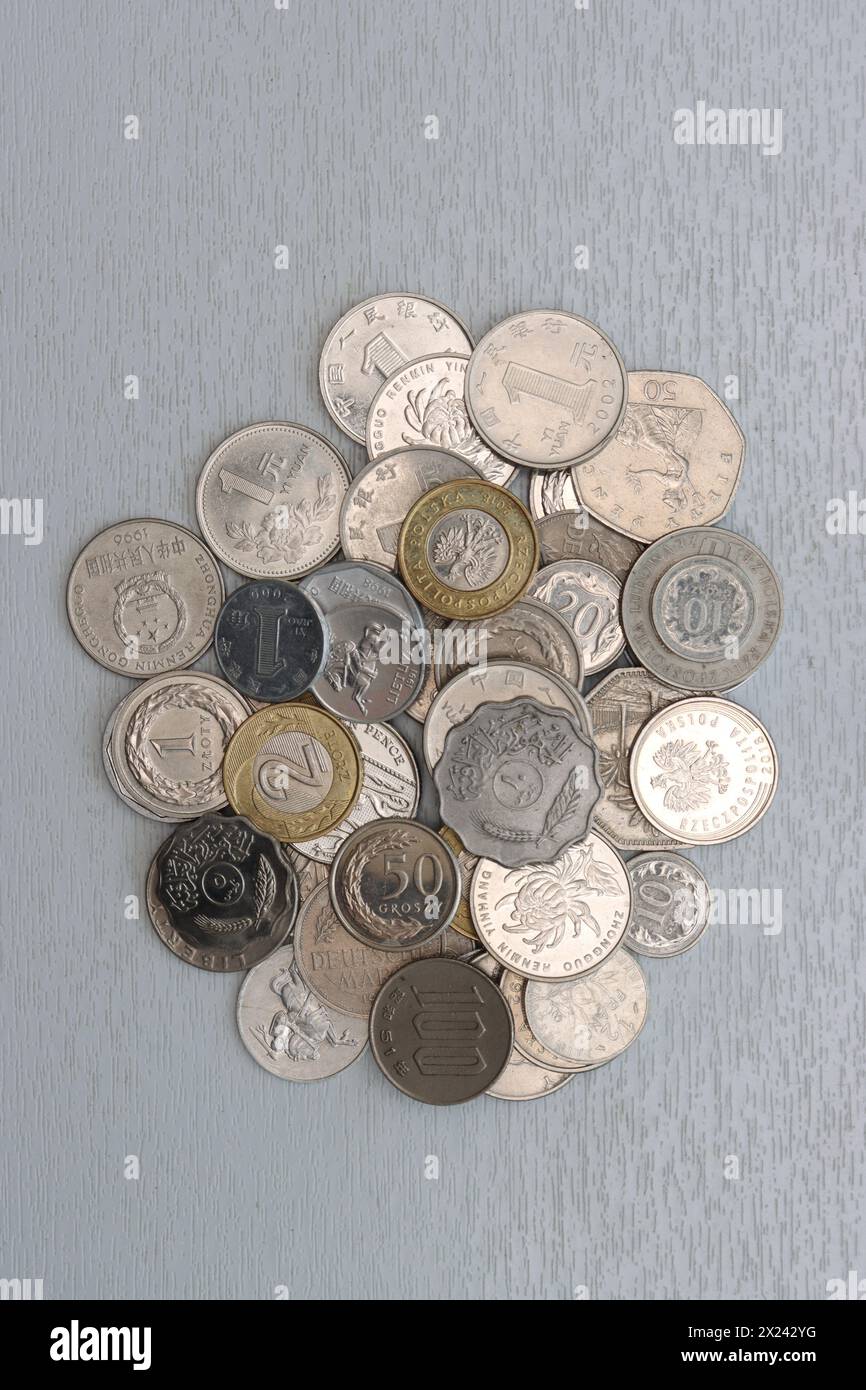 Vertical photo of a variety of metal coins on a light background, top ...