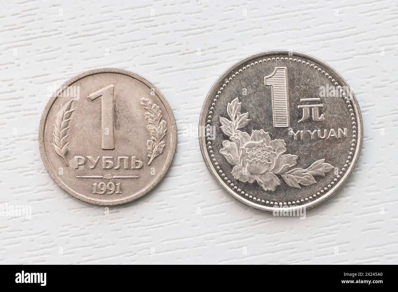 1 Chinese Yuan coin. One Russian ruble. Two white coins lie on a white ...