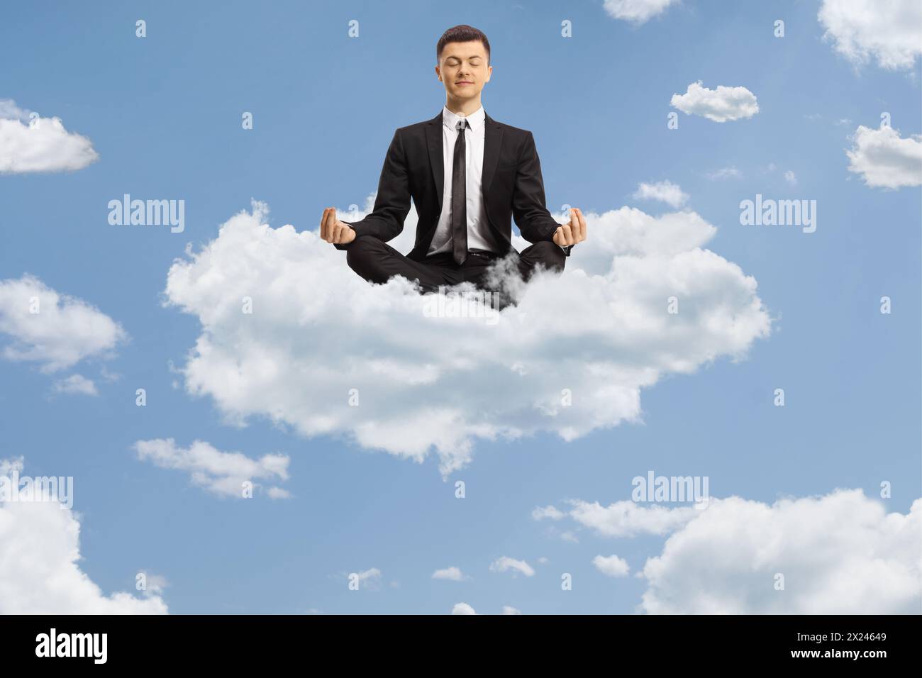Young man in a black suit sitting with crossed legs and floating on a ...