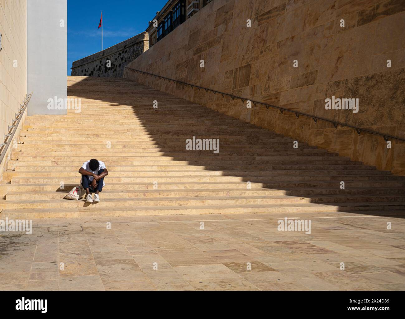 Valletta, Malta, April 04, 2024. a man sitting on the steps of a city ...