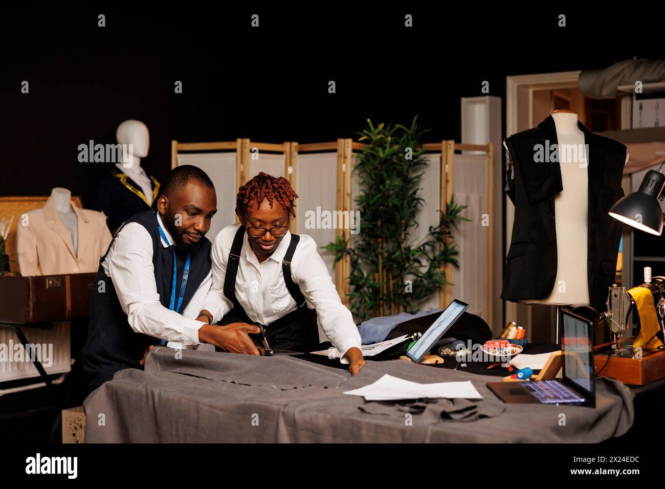 Well dressed couturiers cutting premium fabric in tailoring studio ...