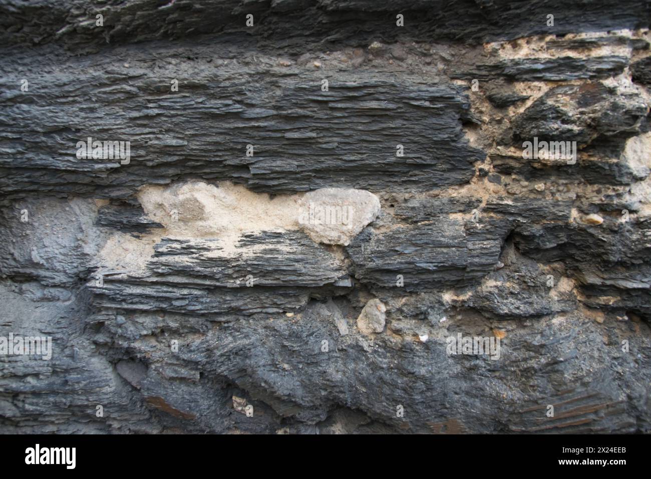 Gray structural stone wall of the ancient building consists of old dark ...