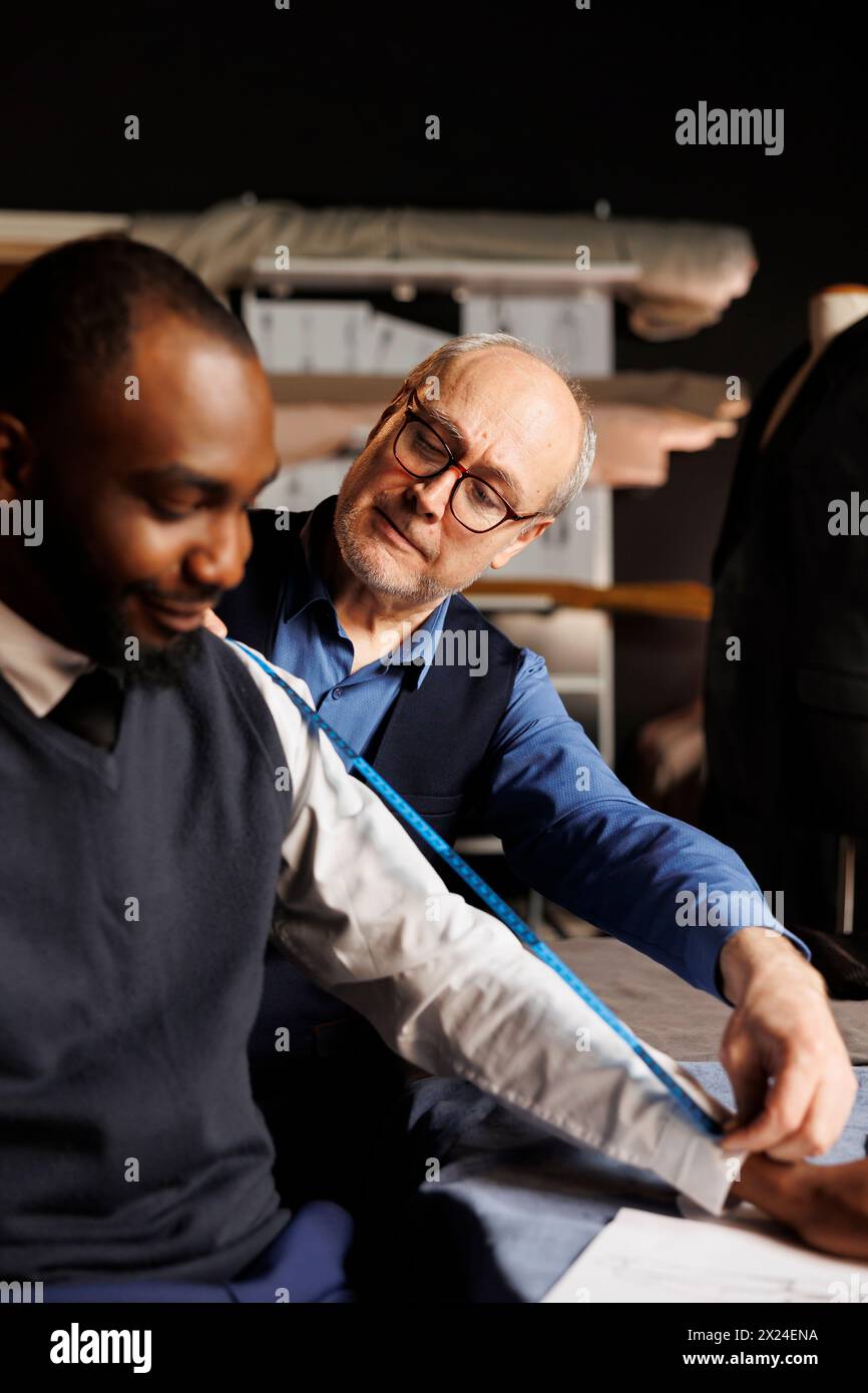 Businessman getting arm measurements taken by precise senior suitmaker ...