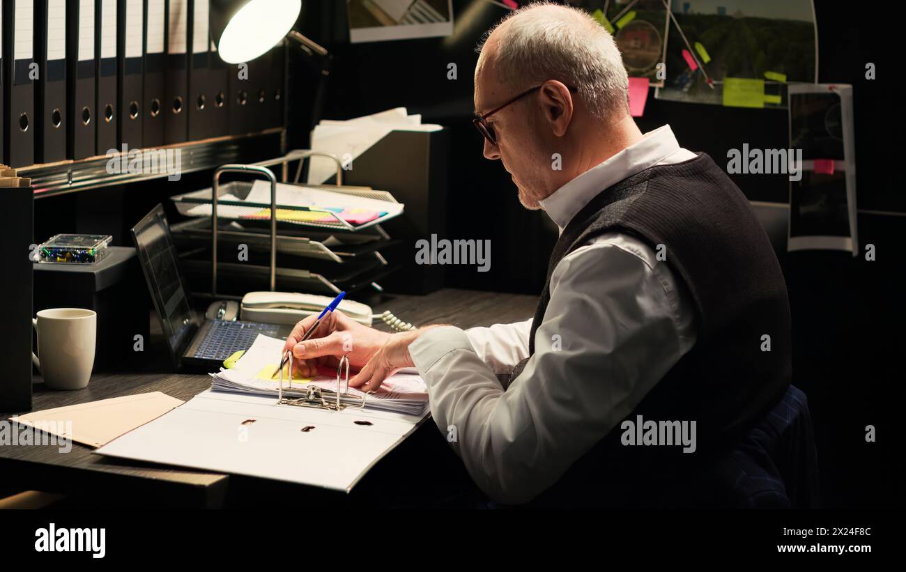 Law agent takes notes on files, writing clues from classified records ...