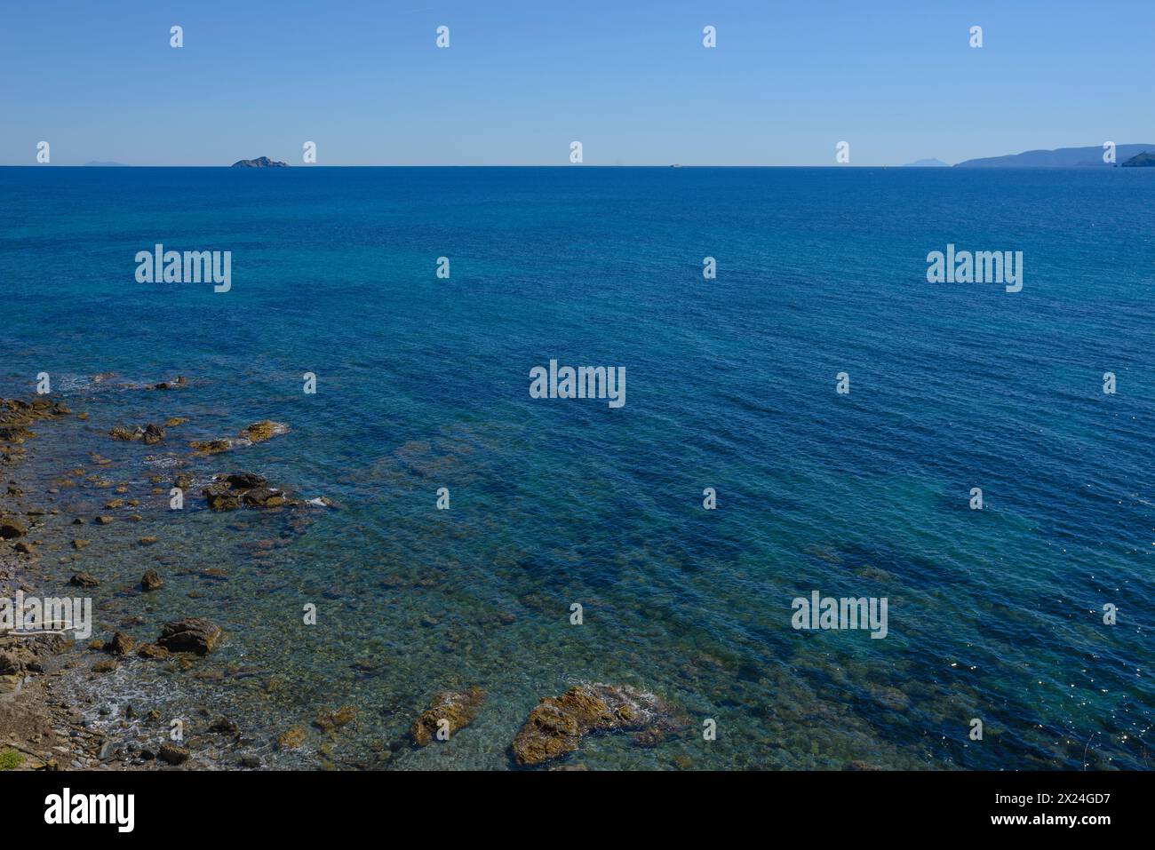 The blue sea and rocky beach in the Piombino canal, Tuscany, Italy ...