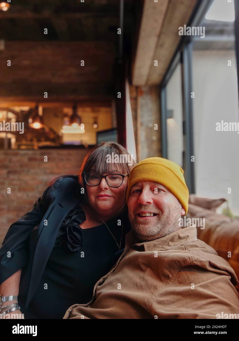 Happy couple sat cuddled up to each other smiling and happy Stock Photo ...
