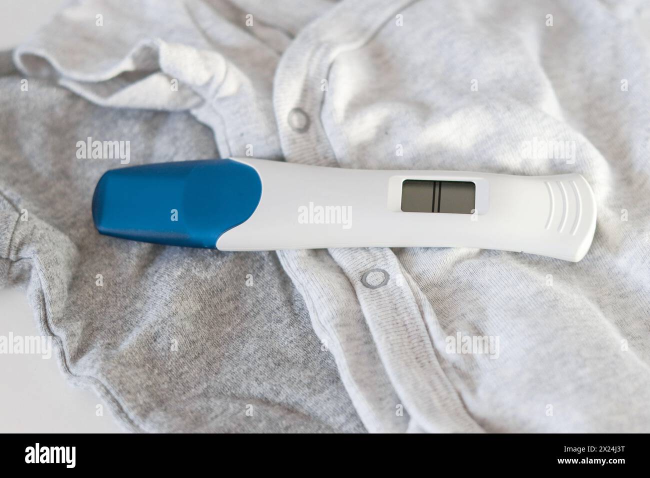 Close up of a digital positive pregnancy test on baby clothes Stock ...
