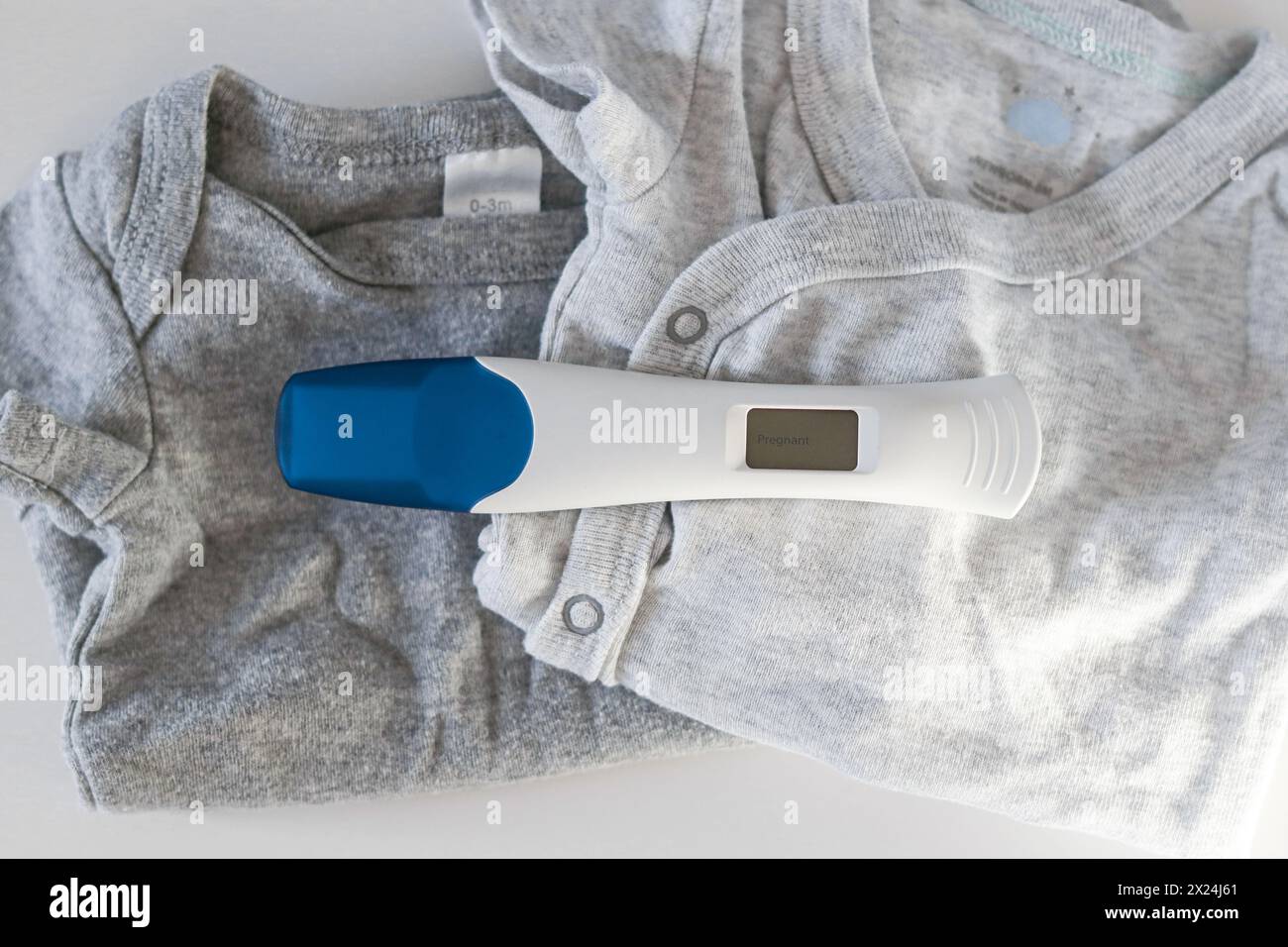 Close up of a digital positive pregnancy test on baby clothes Stock ...