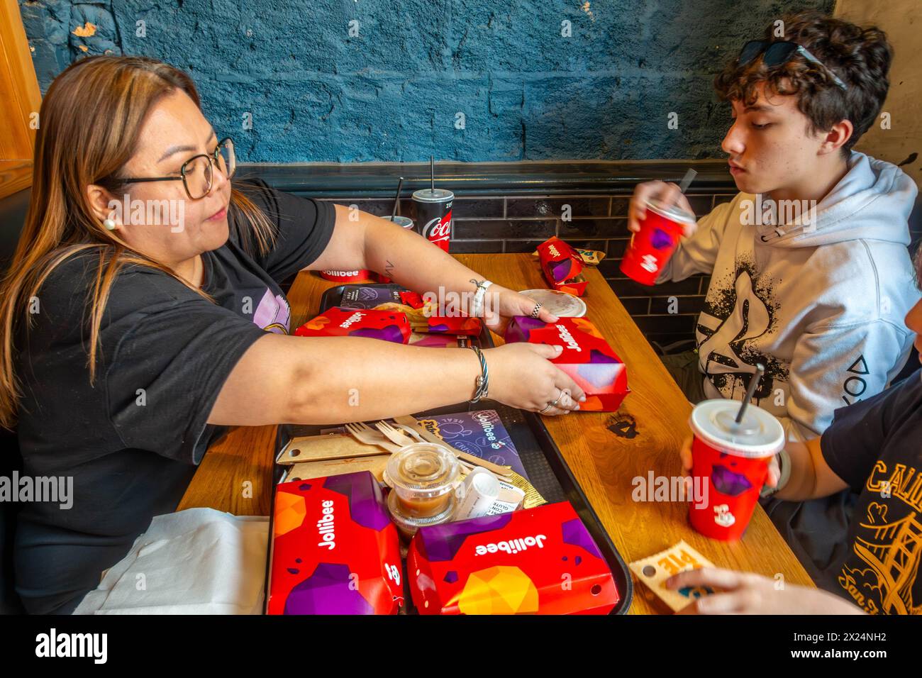 A family share a meal of fried chicken together in a Jollibee ...