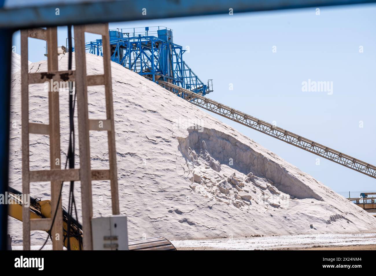 Industrial machinery crowns a salt pile, with conveyors and structures ...