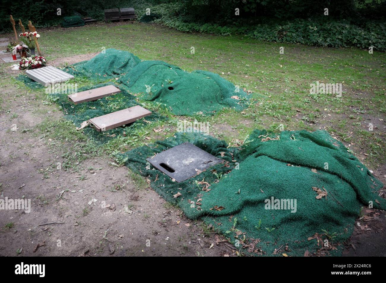 several urn graves lined with green mats and provided with protective ...