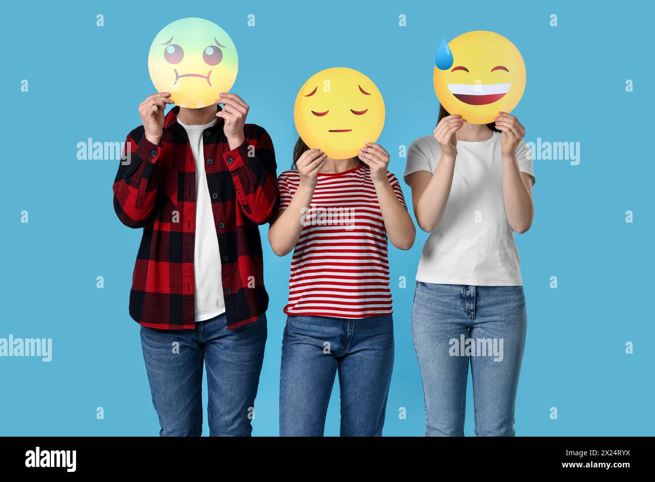 People covering faces with emoticons on light blue background Stock ...