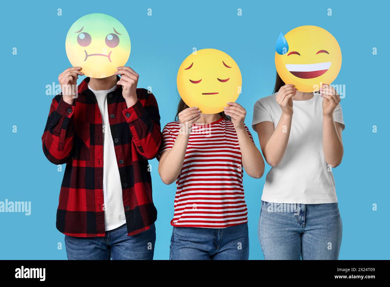 People covering faces with emoticons on light blue background Stock ...