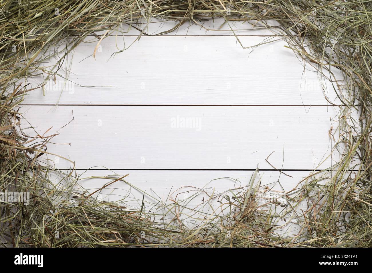 Frame made of dried hay on white wooden table, top view. Space for text ...