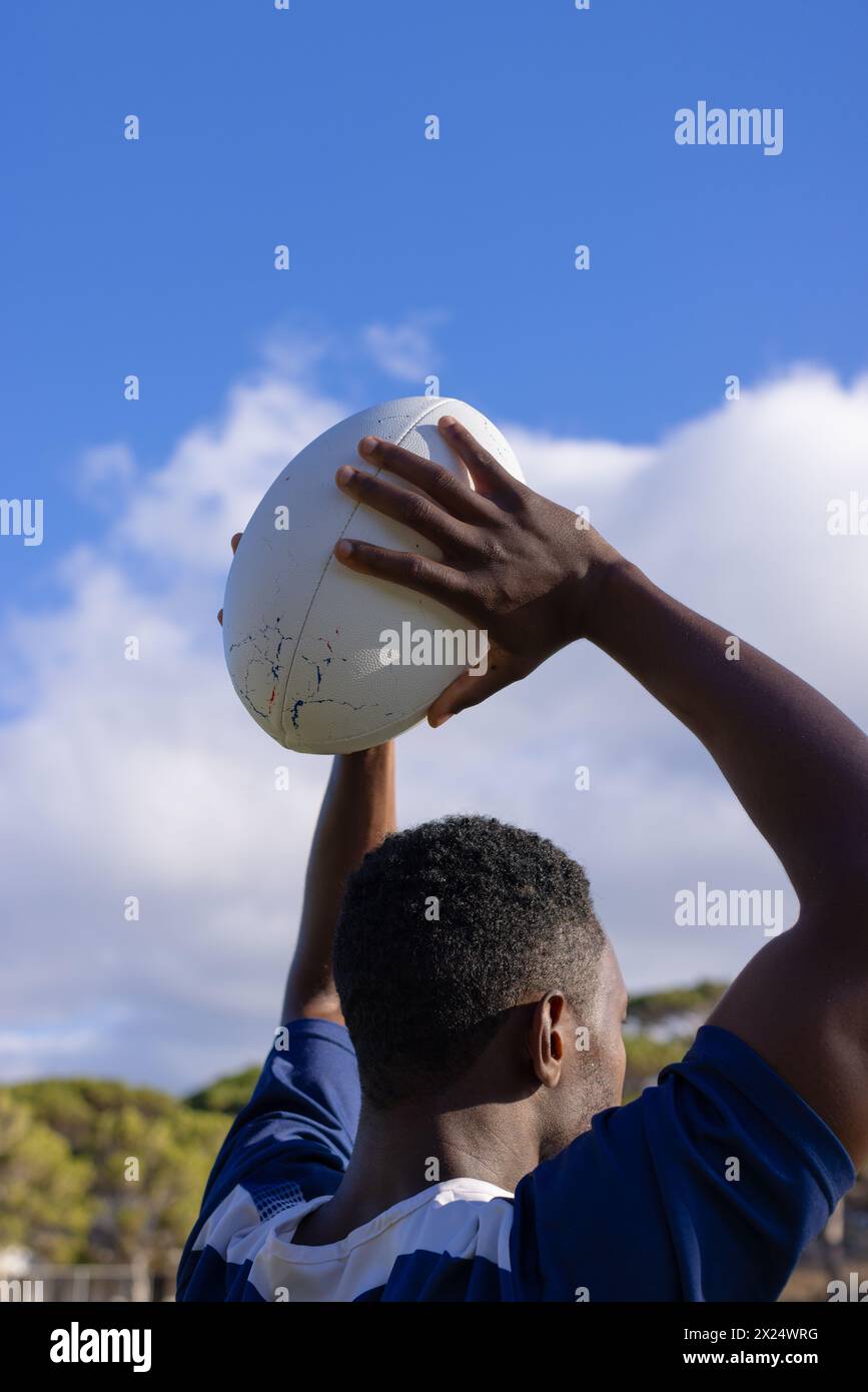 African American young male athlete holding a rugby ball, ready to ...