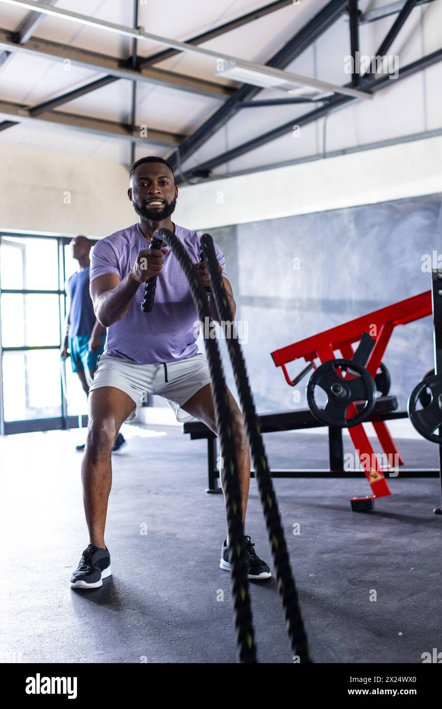 Two African American young male athletes are training with battle ropes ...