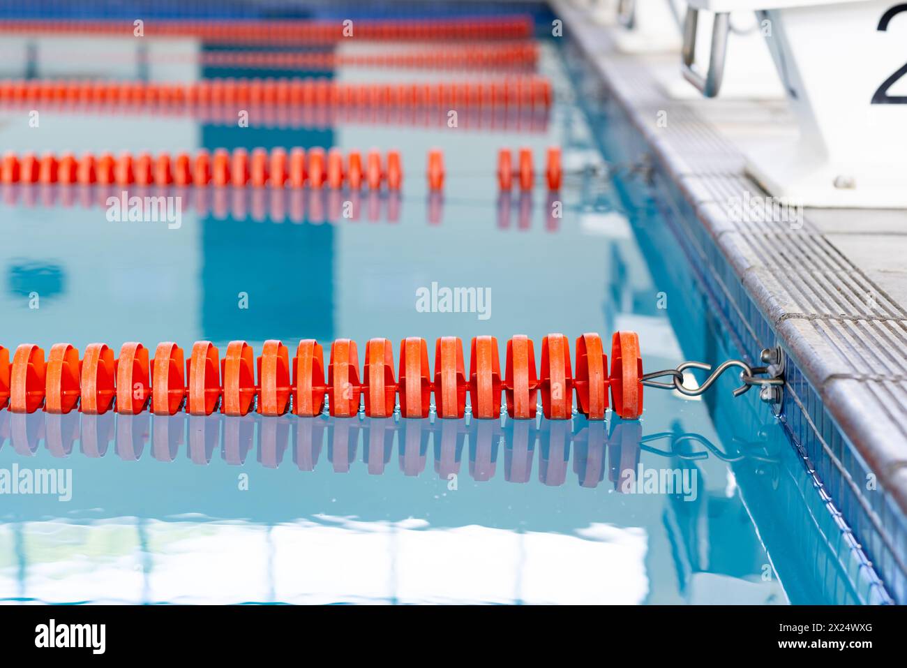 Indoors, orange lane dividers stretch across calm swimming pool water ...