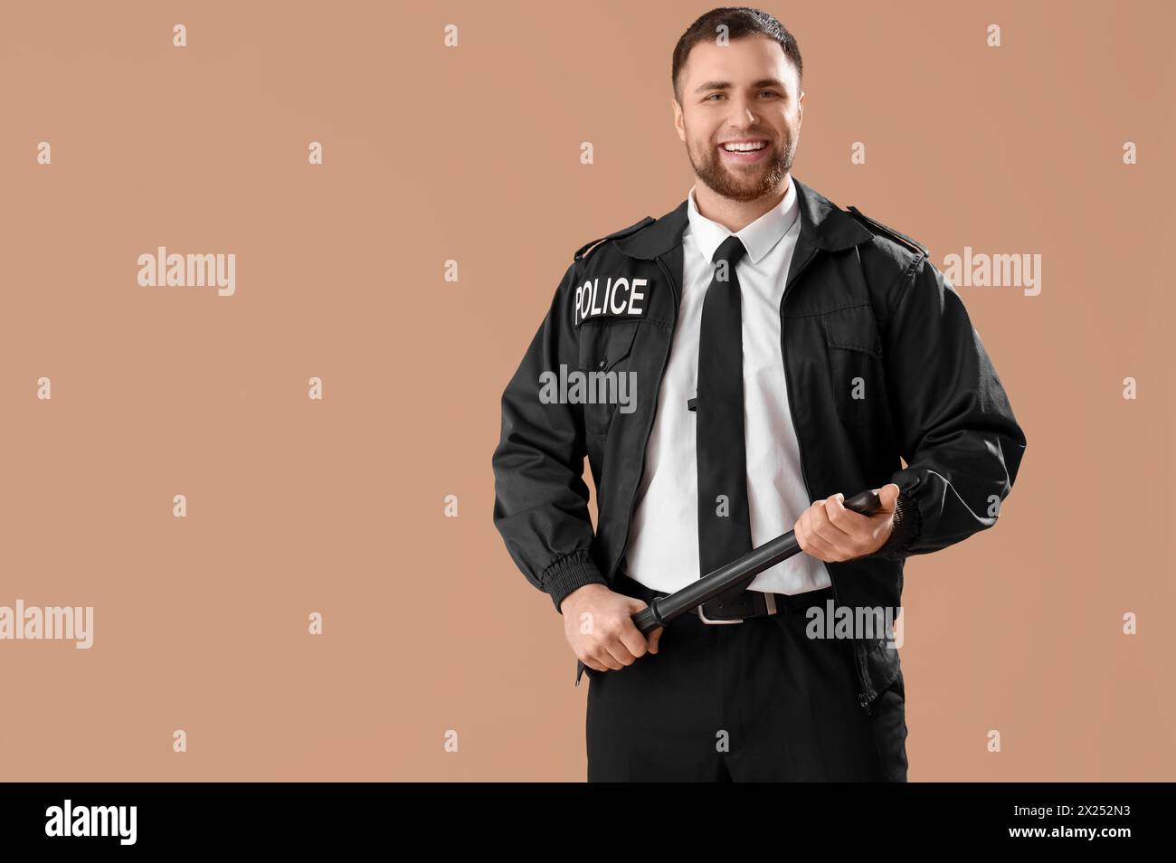 Male police officer with baton on beige background Stock Photo - Alamy