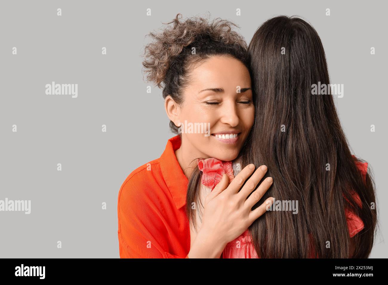 Beautiful mature woman hugging her teenage daughter on grey background. Mother's day Stock Photo ...