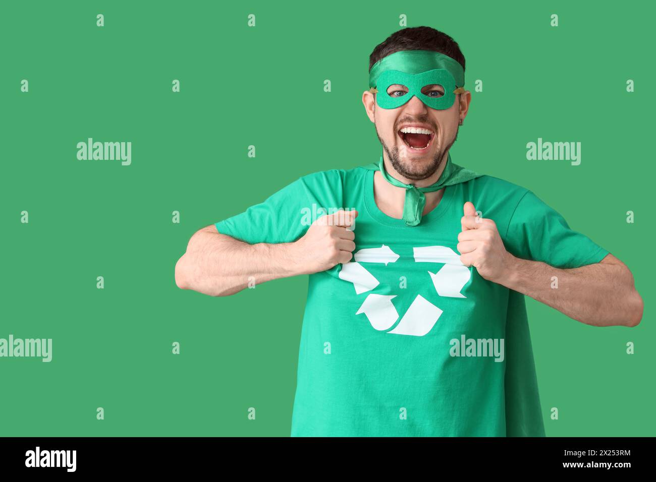 Enthusiastic young man dressed as eco superhero on green background ...