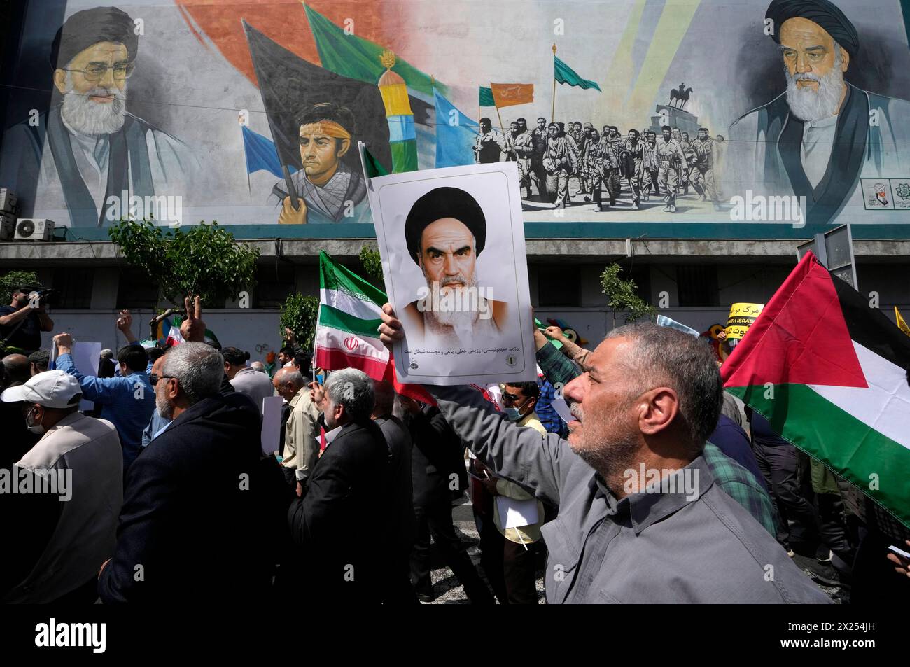FILE - Iranian worshippers walk past a mural showing the late ...
